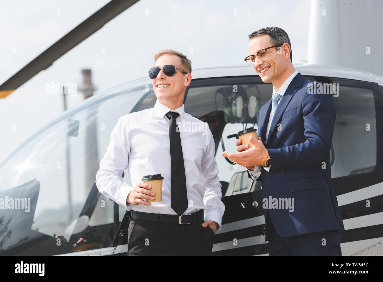 smiling Pilot in sunglasses and businessman with coffee to go near ...