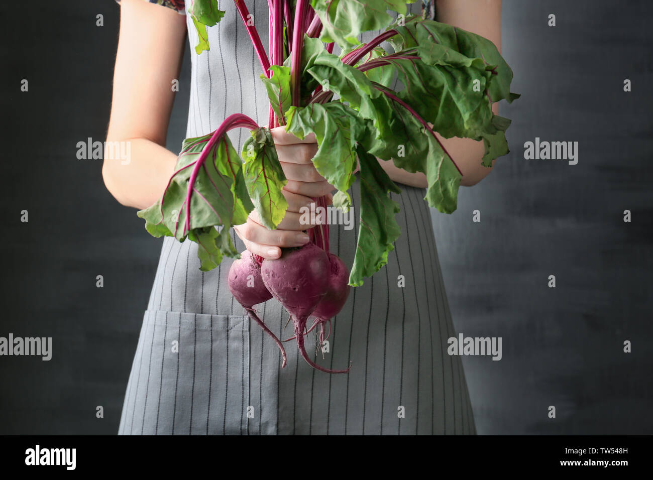 Woman holding young beets on grey background Stock Photo - Alamy