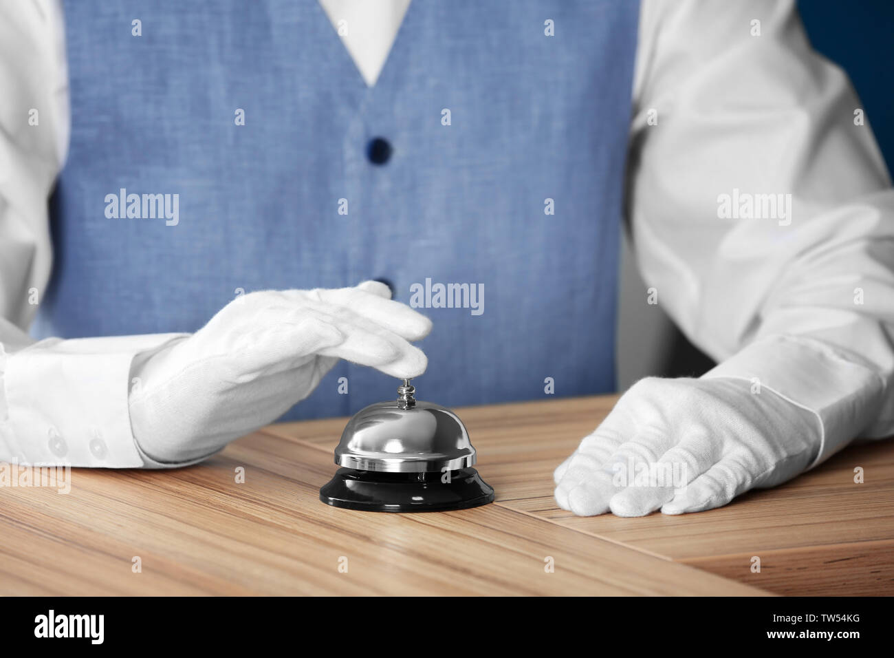 Man ringing a service bell on wooden table Stock Photo - Alamy