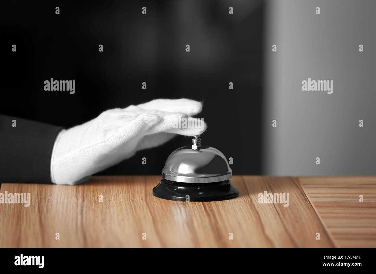 Man ringing service bell on wooden table Stock Photo - Alamy