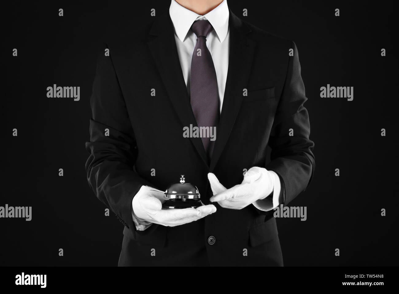Man holding bell on black background Stock Photo - Alamy