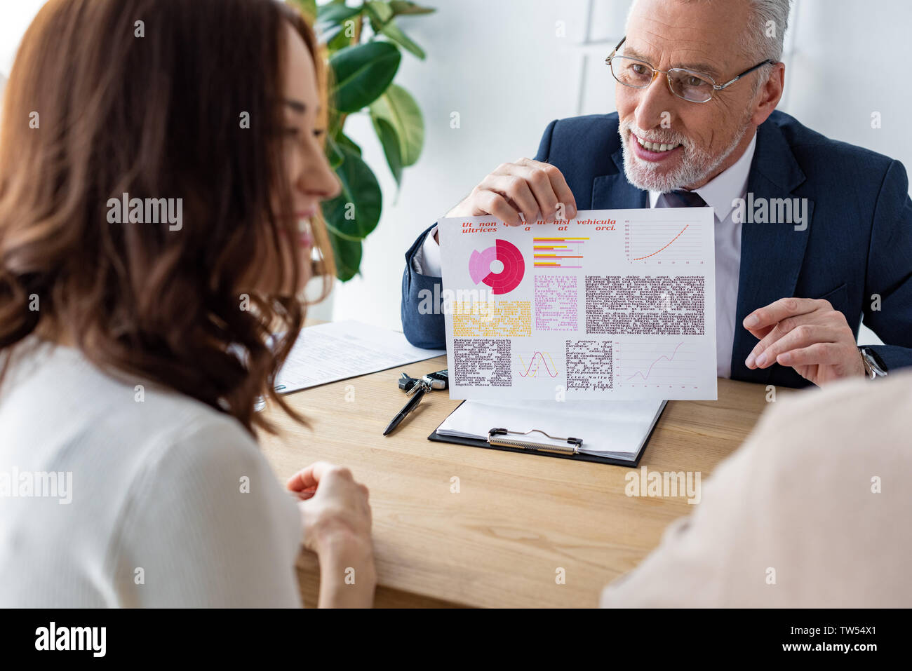 selective focus of happy car dealer holding charts and graphs near ...