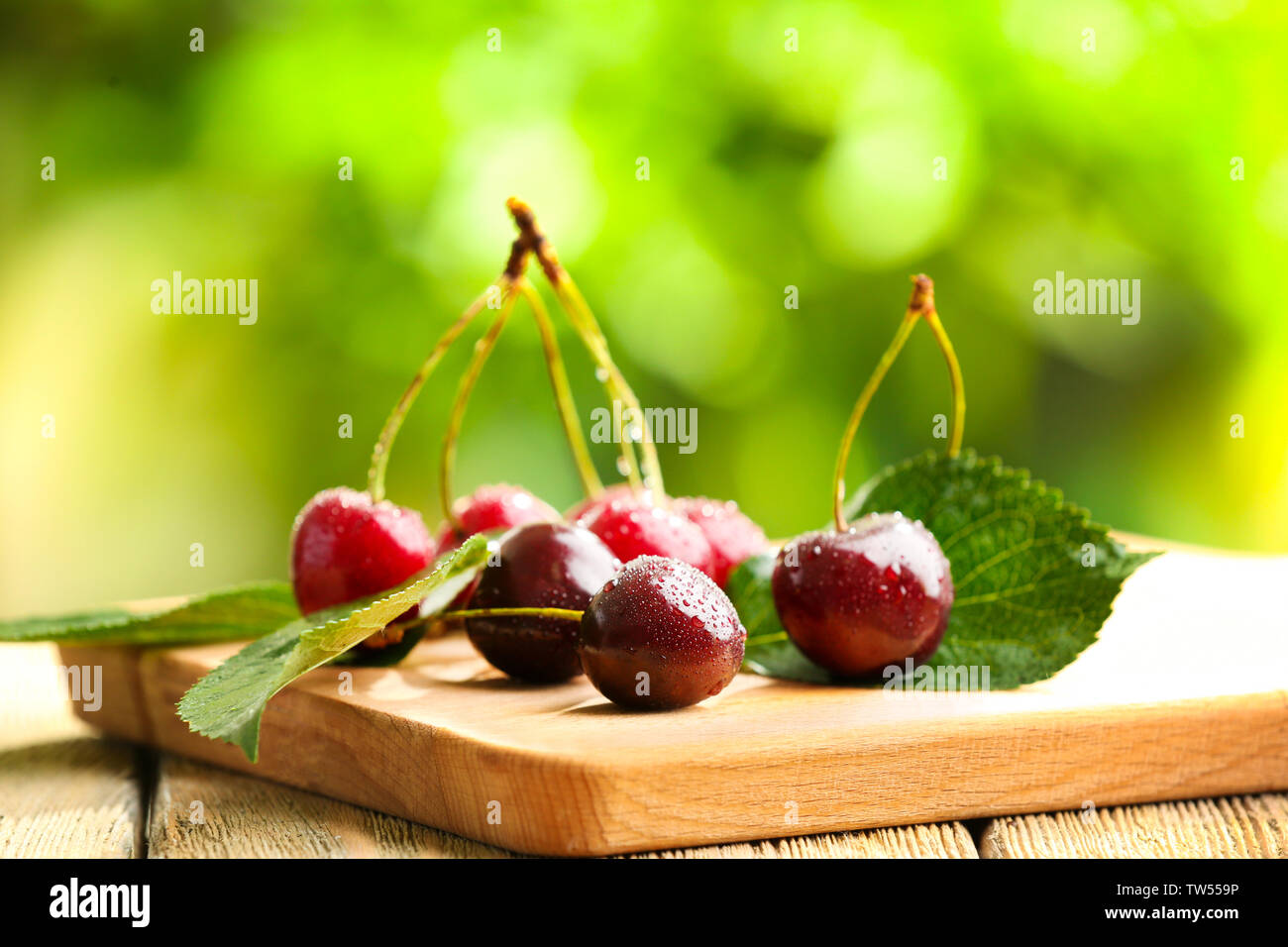 Wooden board with fresh cherry on table outdoors Stock Photo - Alamy