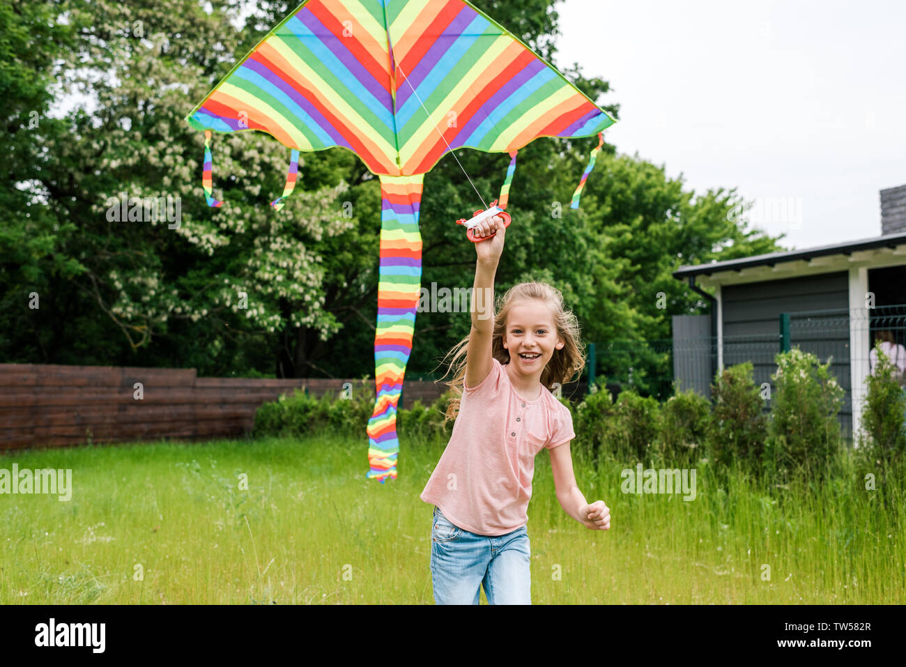 cheerful child running with colorful kite on green grass outside Stock ...
