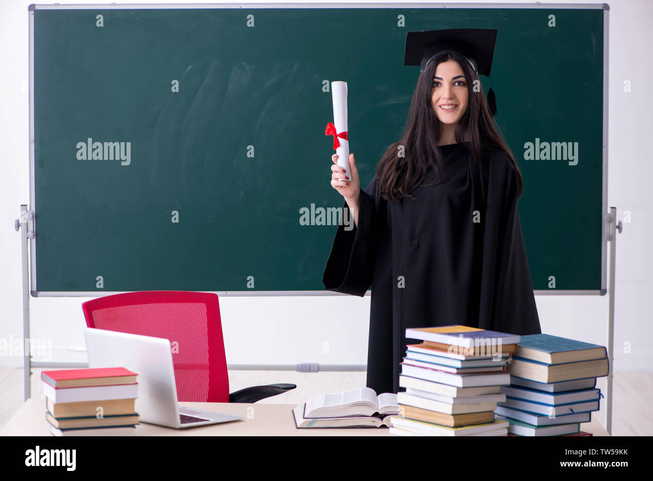 Female graduate student in front of green board Stock Photo - Alamy