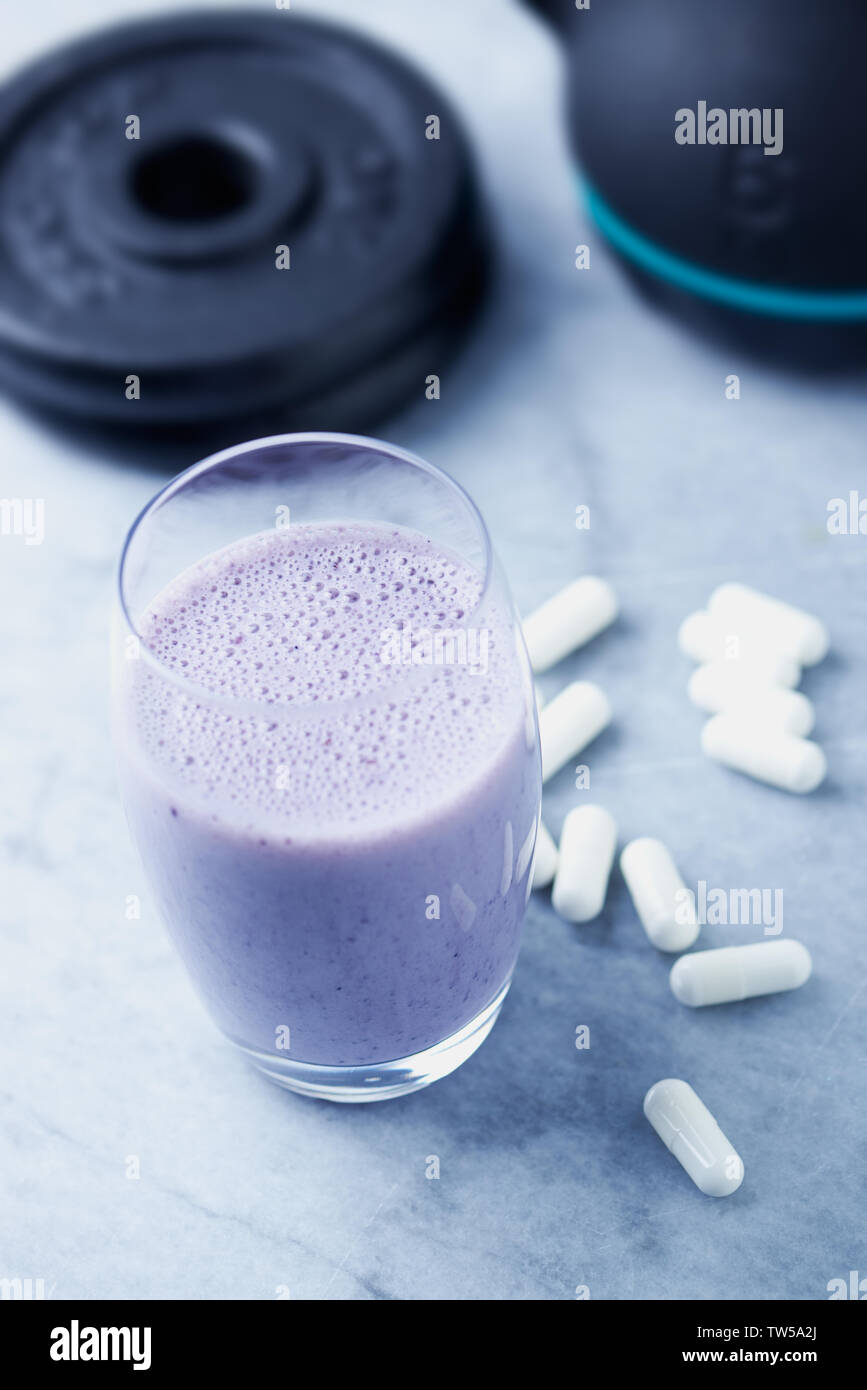 Glass of Protein Shake with milk and blueberries. Creatine capsules ...