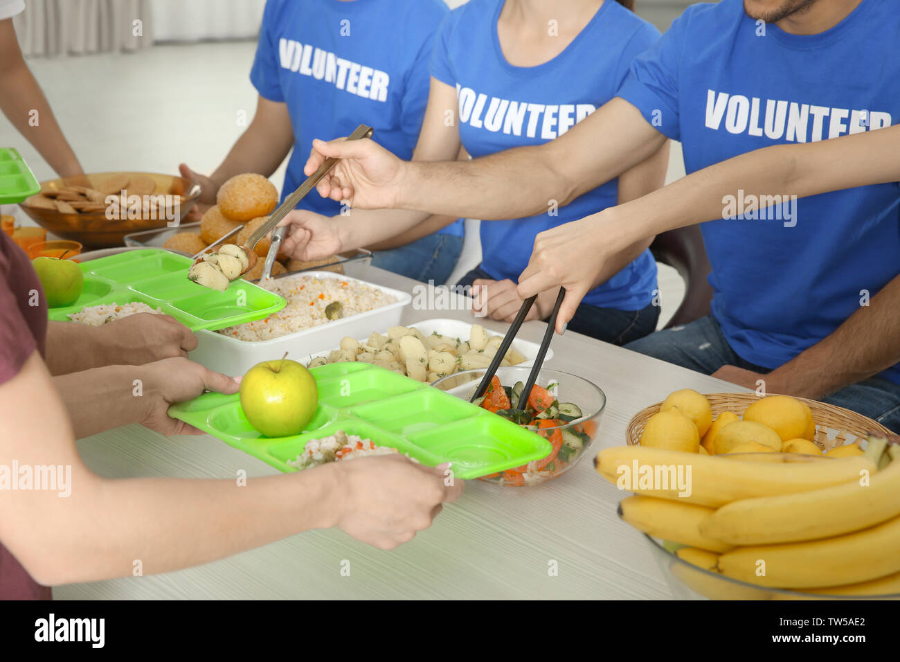 Volunteers serving food for homeless people indoors Stock Photo - Alamy