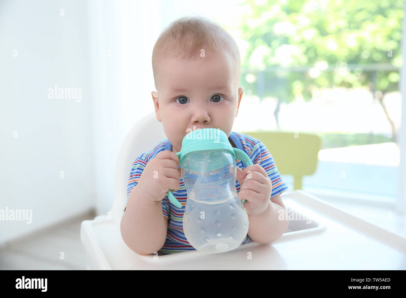 Cute baby drinking water from plastic bottle indoors Stock Photo - Alamy