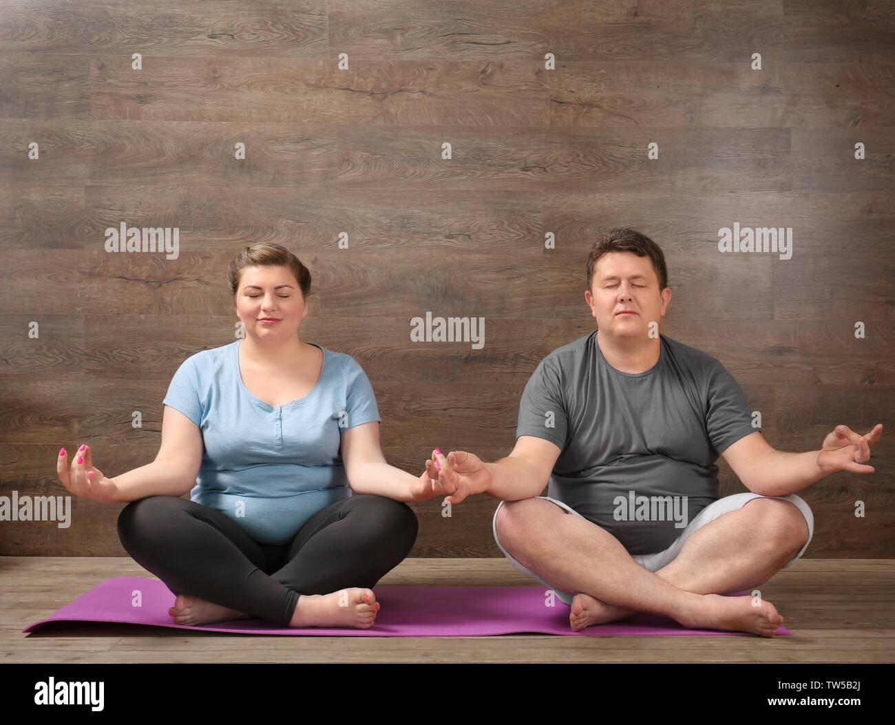Overweight couple training together against wooden wall Stock Photo - Alamy