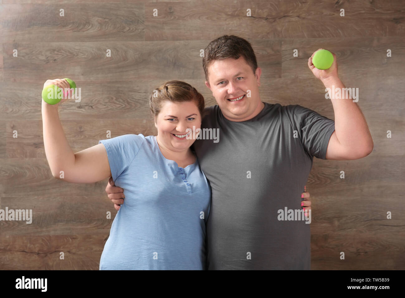 Overweight couple training together on wooden background Stock Photo ...