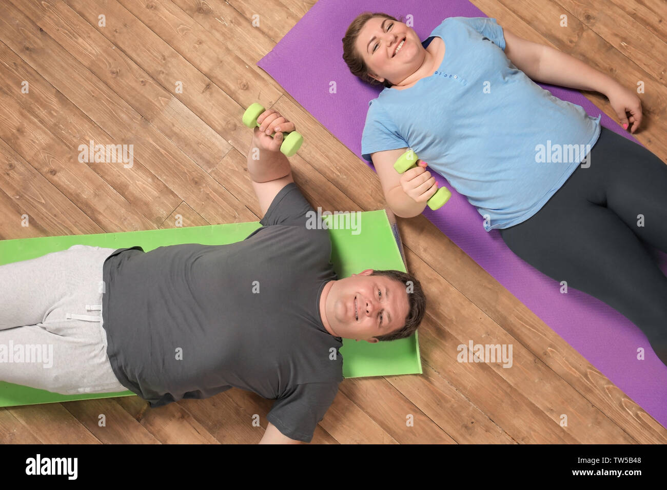Overweight couple training together on wooden floor Stock Photo - Alamy