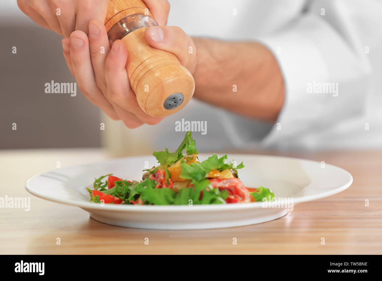 Male chef adding spices to salad in kitchen, closeup Stock Photo - Alamy