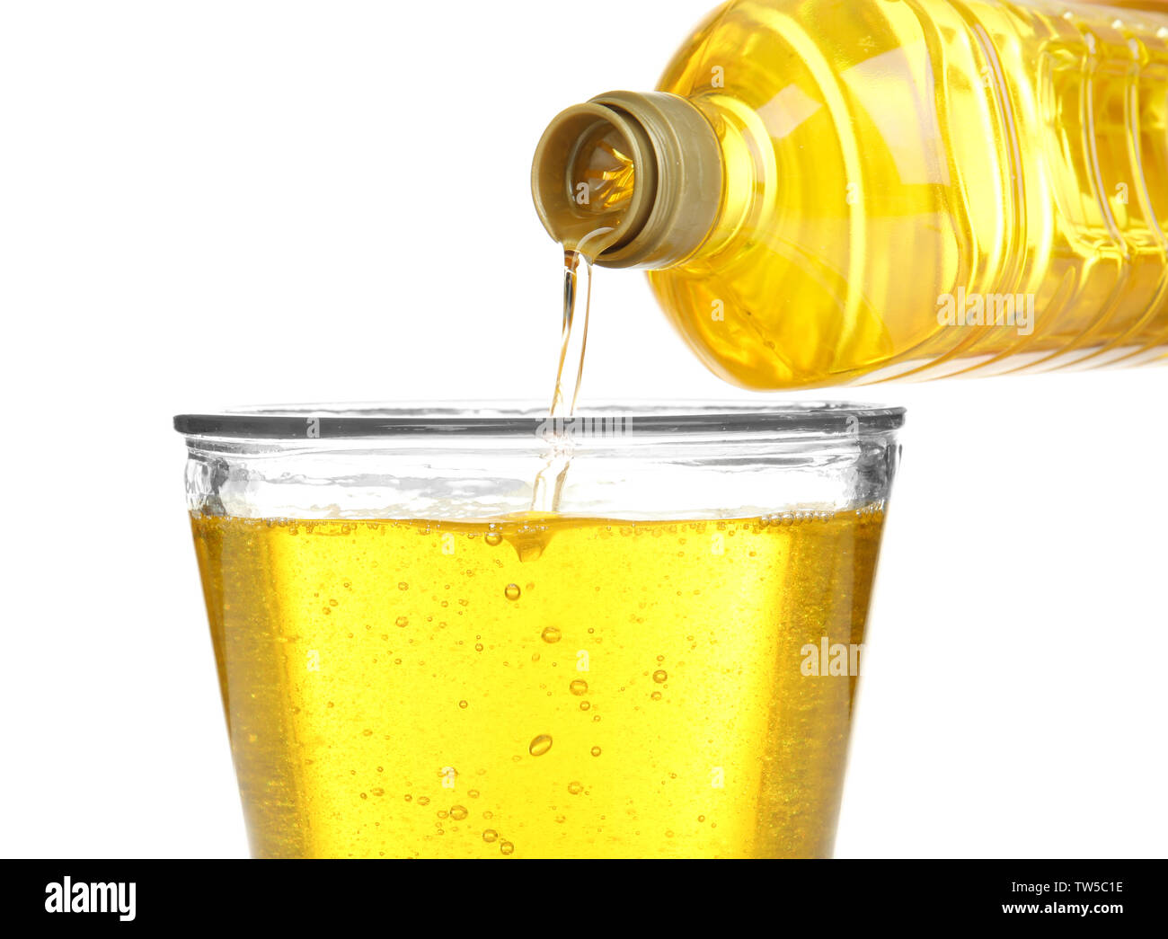 Pouring cooking oil into glass on white background Stock Photo - Alamy