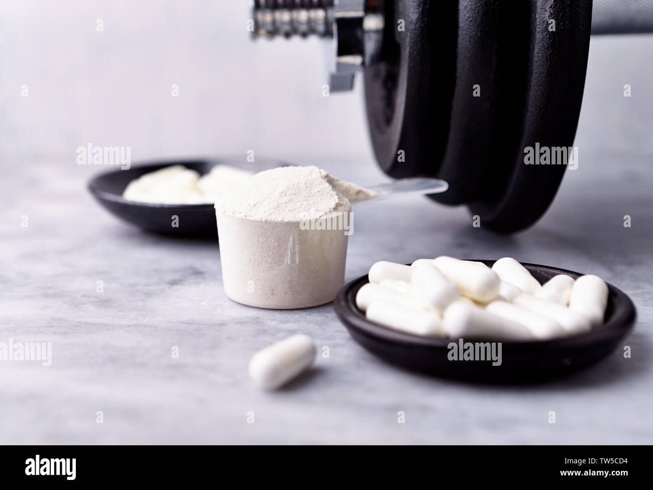 Scoop of Whey Protein, Creatine, Taurine capsules and a dumbbell Stock ...