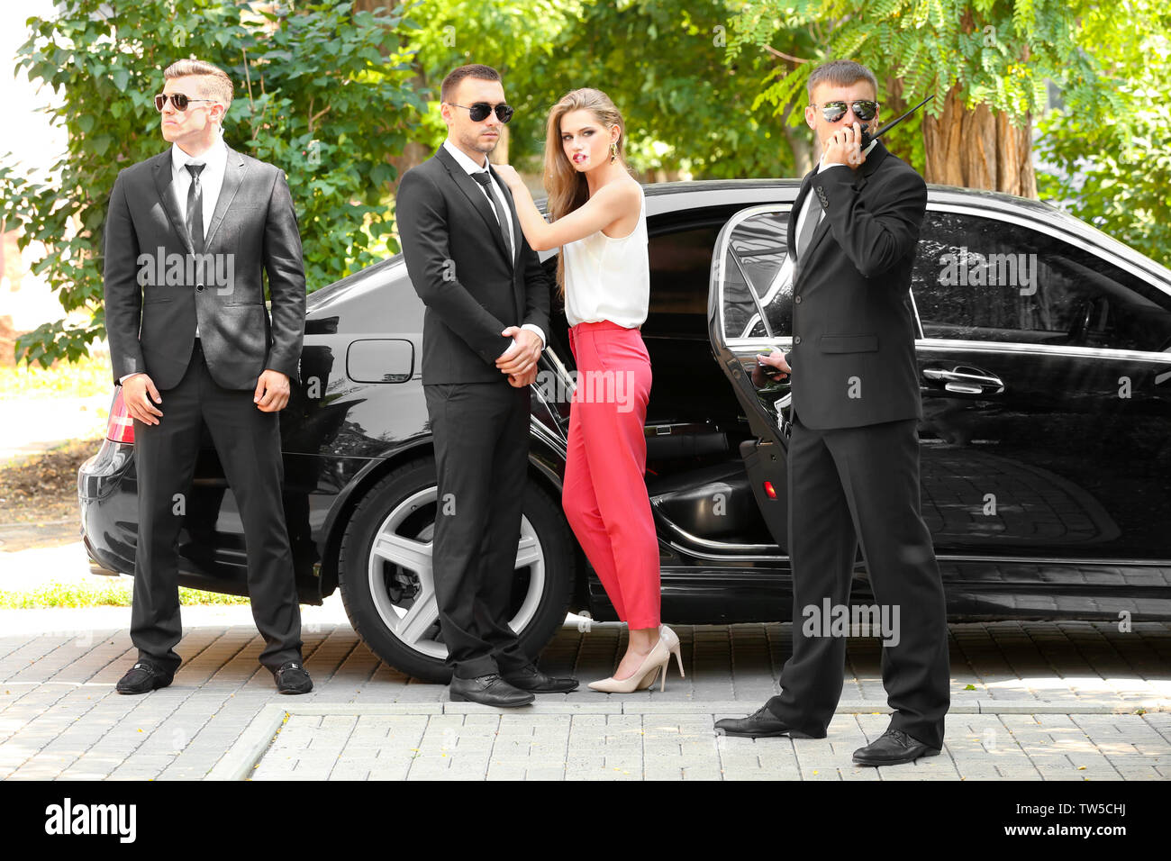 Young businesswoman with bodyguards near car outdoors Stock Photo - Alamy