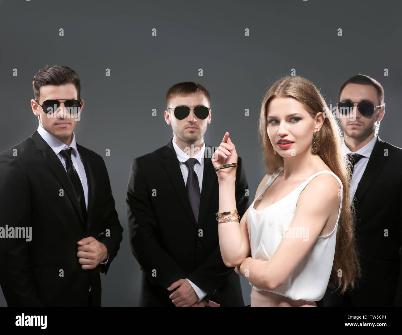 Famous celebrity with bodyguards on grey background Stock Photo - Alamy