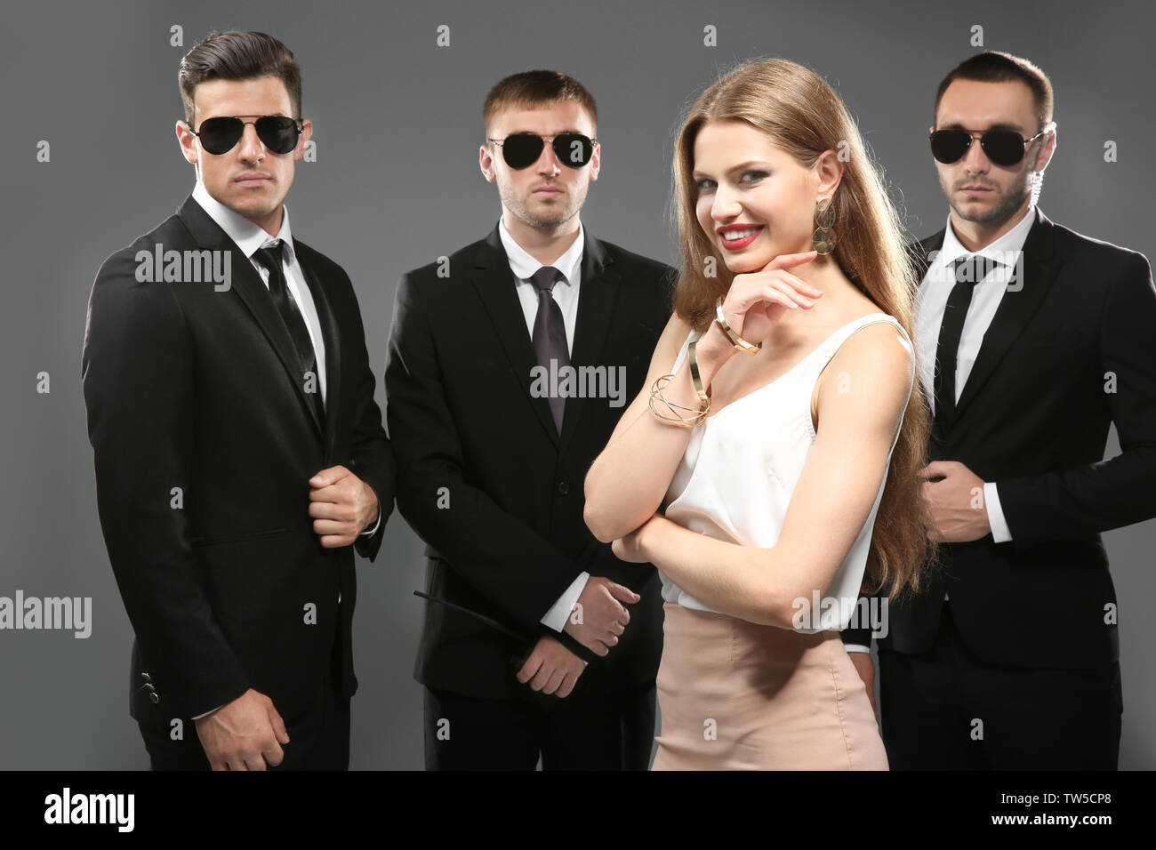 Famous celebrity with bodyguards on grey background Stock Photo - Alamy