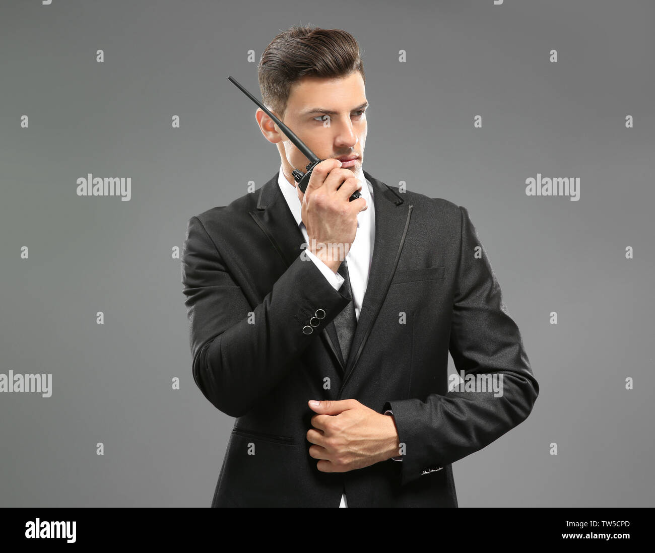Handsome security guard on grey background Stock Photo - Alamy
