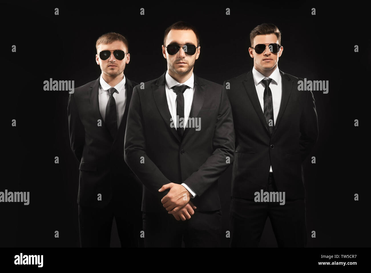 Handsome bodyguards on dark background Stock Photo - Alamy