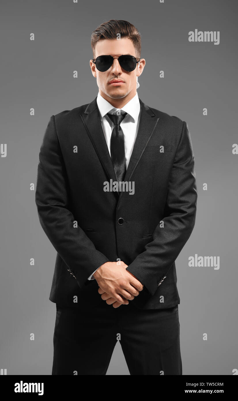 Handsome security guard on grey background Stock Photo - Alamy