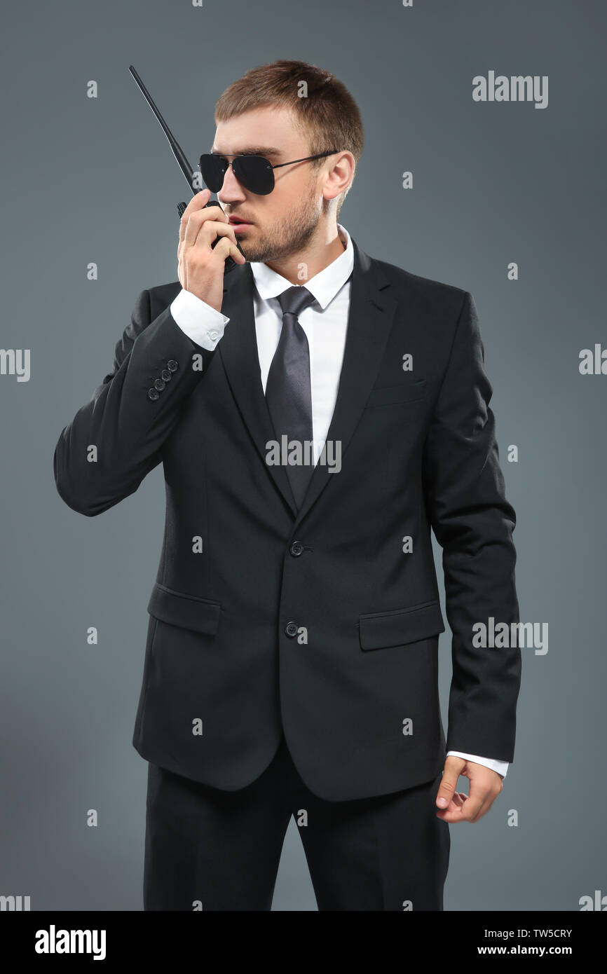 Handsome security guard on grey background Stock Photo - Alamy