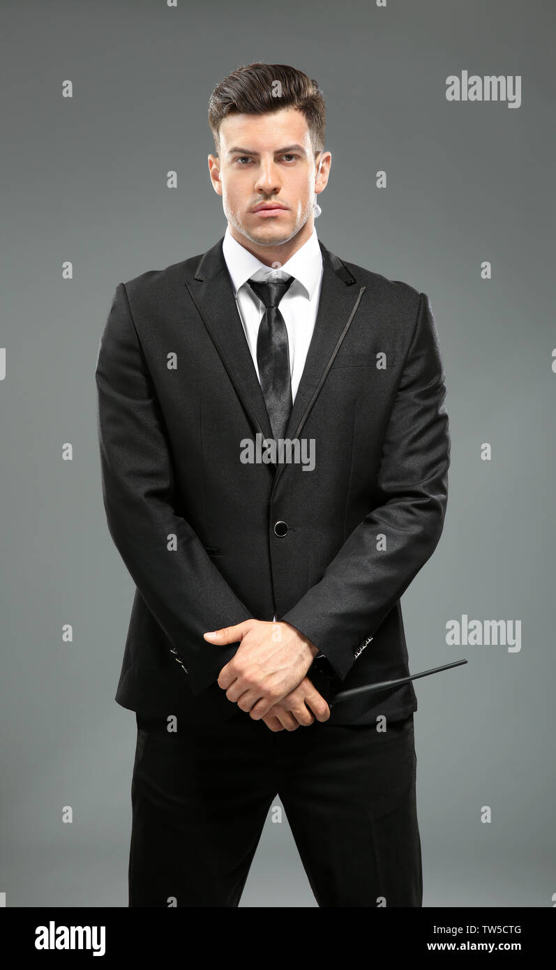 Handsome security guard on grey background Stock Photo - Alamy