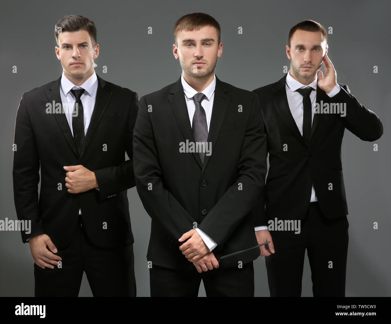 Handsome bodyguards on grey background Stock Photo - Alamy