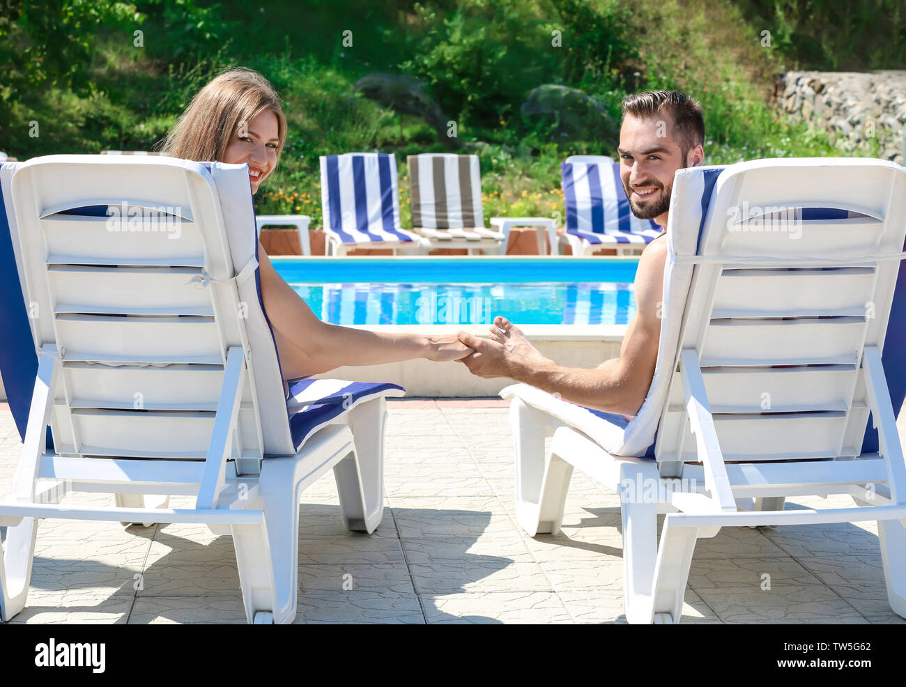 Couple sitting near swimming pool hi-res stock photography and images ...