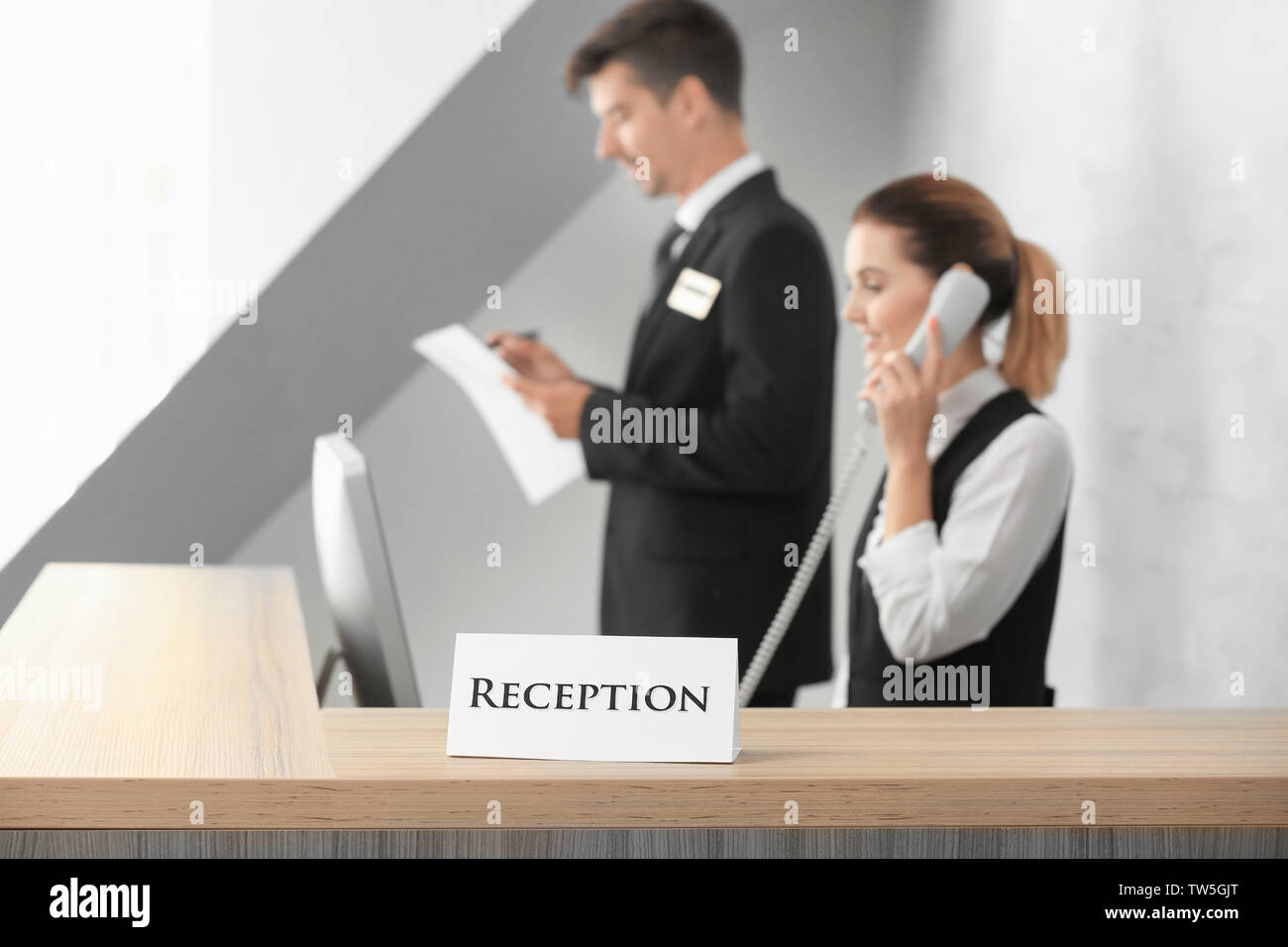 Reception sign and blurred workers at desk in hotel Stock Photo - Alamy