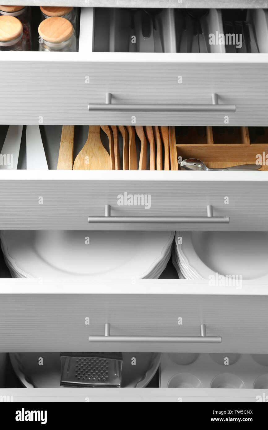 Set of ceramic plates and utensils in kitchen drawers Stock Photo - Alamy