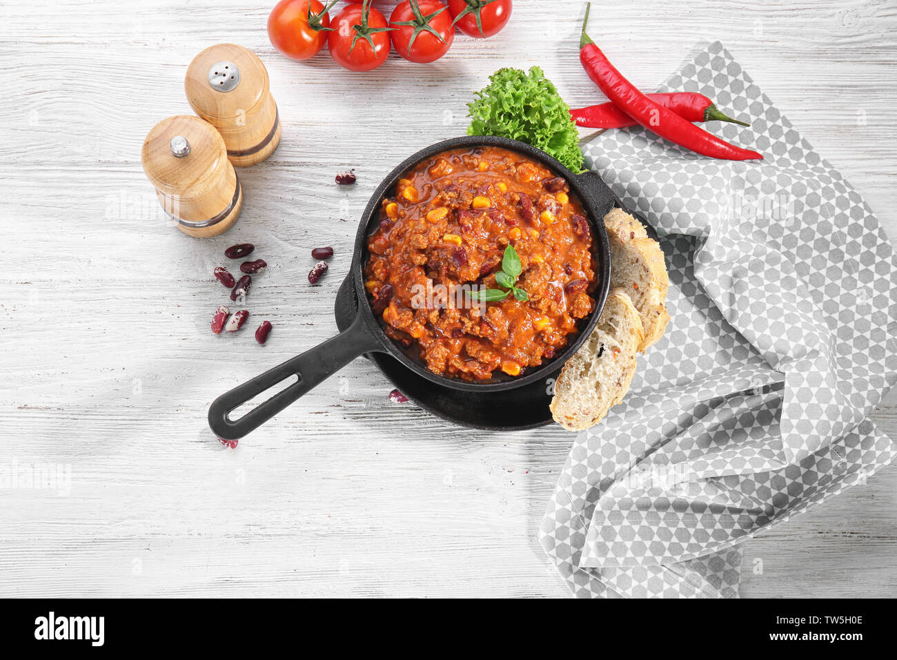 Chili con carne with fresh basil in frying pan on kitchen table Stock ...