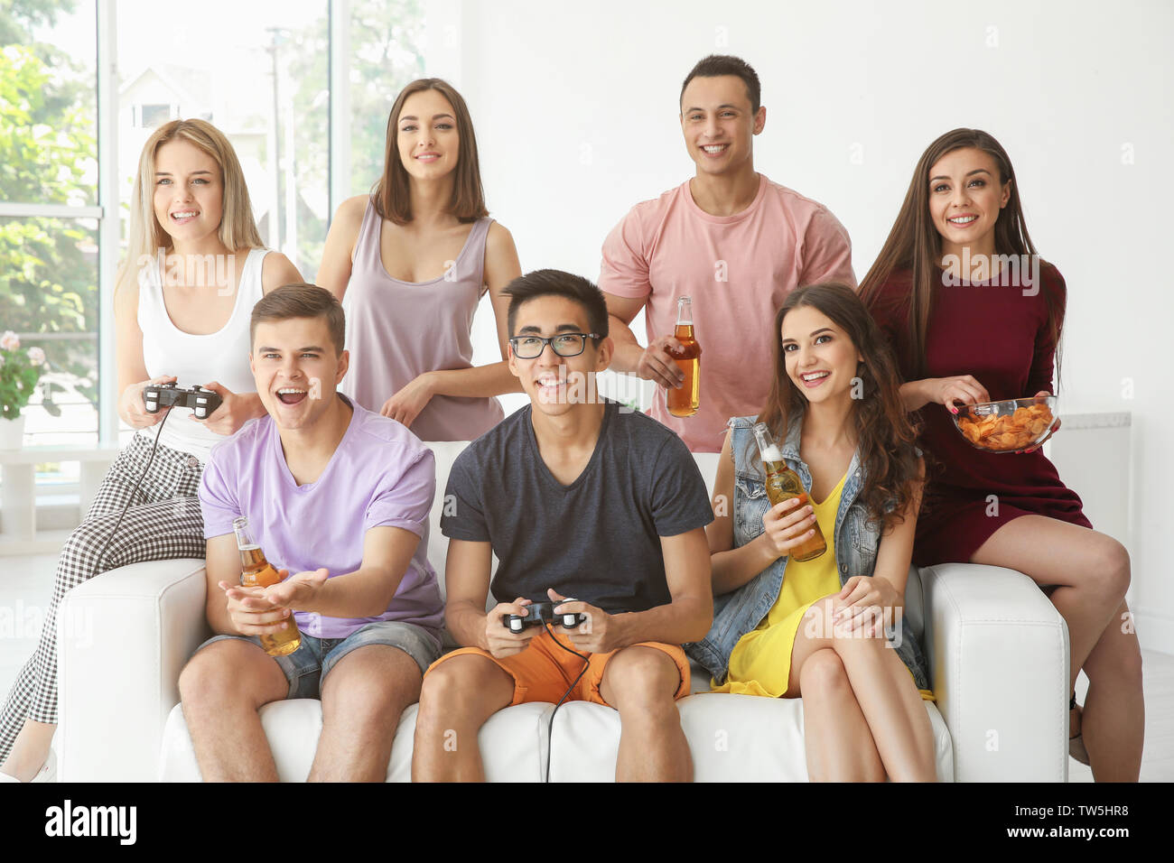 Friends playing video games on TV at home Stock Photo - Alamy