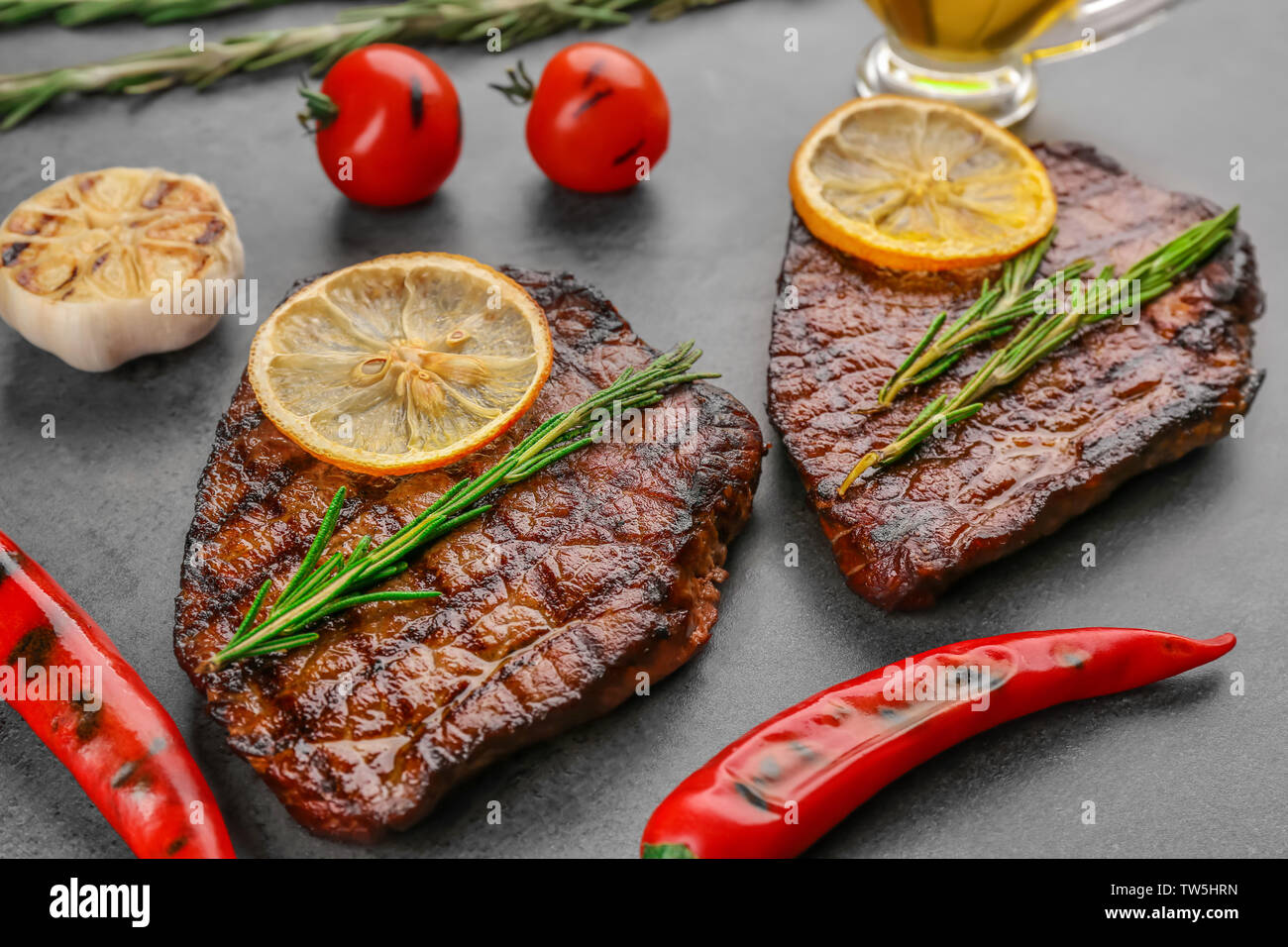 Delicious grilled steaks on dark grunge background Stock Photo - Alamy