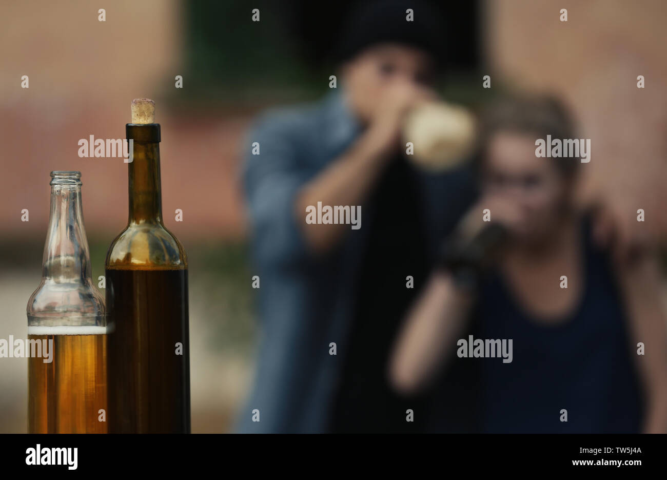 Bottles with alcohol on blurred view of drunk people Stock Photo - Alamy