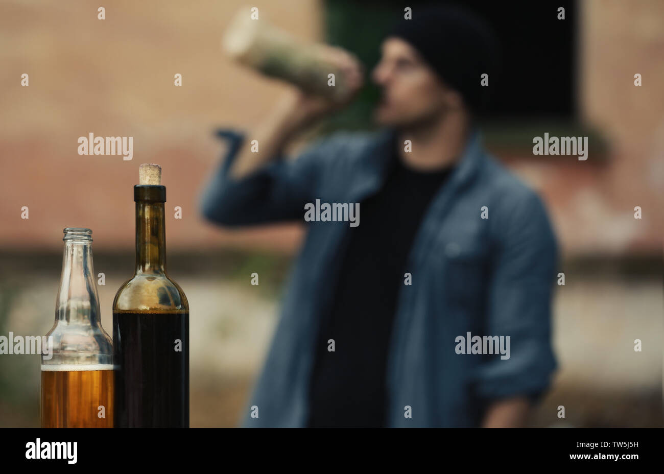 Bottles with alcohol on blurred view of drunk man Stock Photo - Alamy
