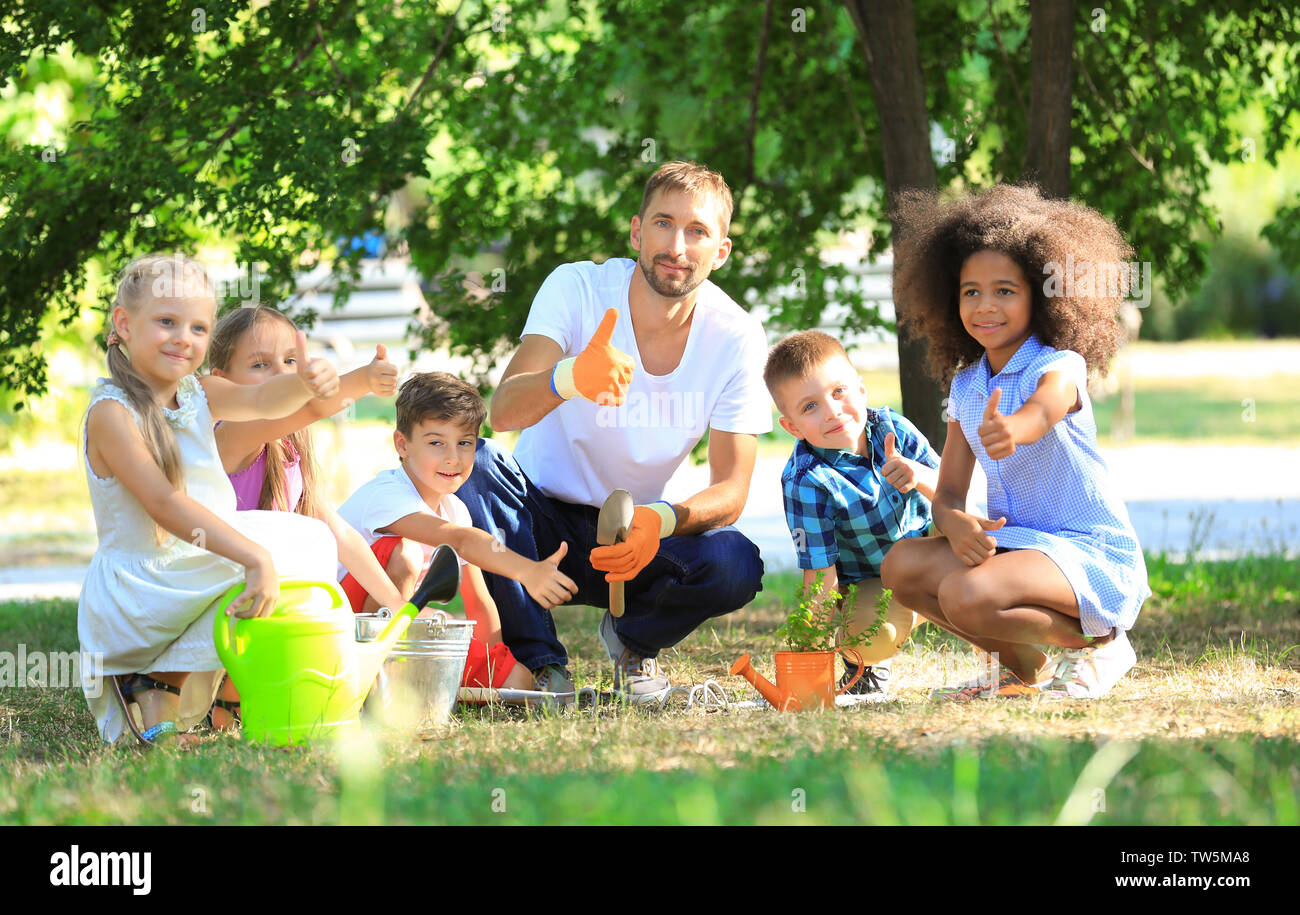 Group of children with teacher planting sapling in park Stock Photo - Alamy