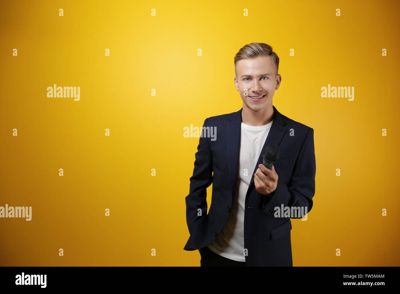 Young presenter with microphone on color background Stock Photo - Alamy