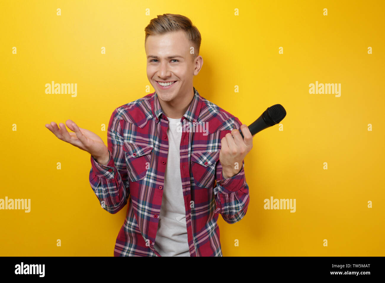 Young presenter with microphone on color background Stock Photo - Alamy