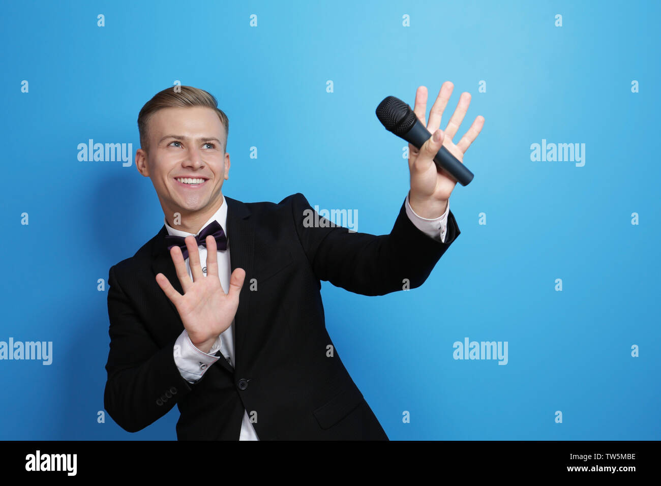 Young presenter with microphone on color background Stock Photo - Alamy