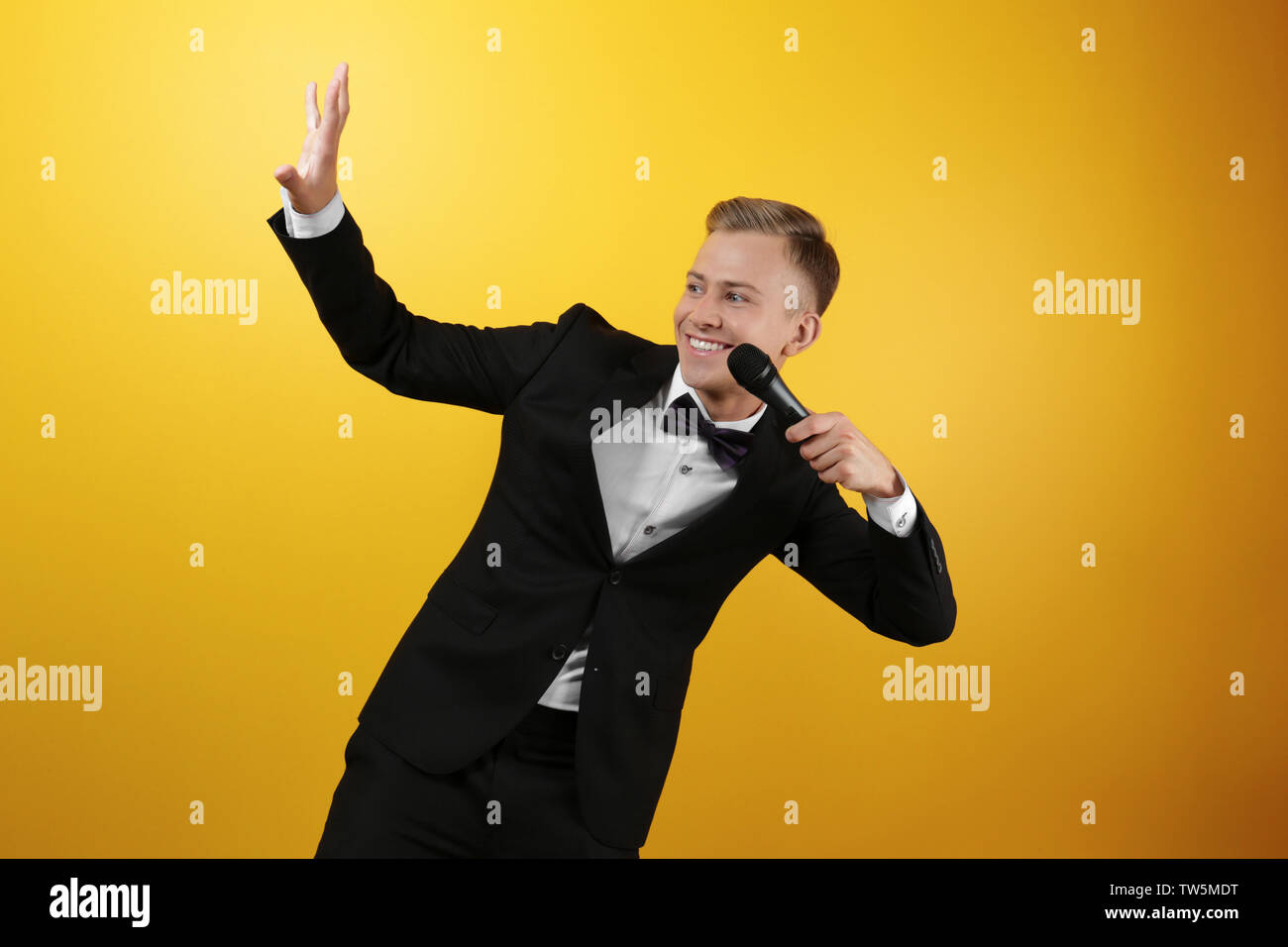 Young presenter with microphone on color background Stock Photo - Alamy