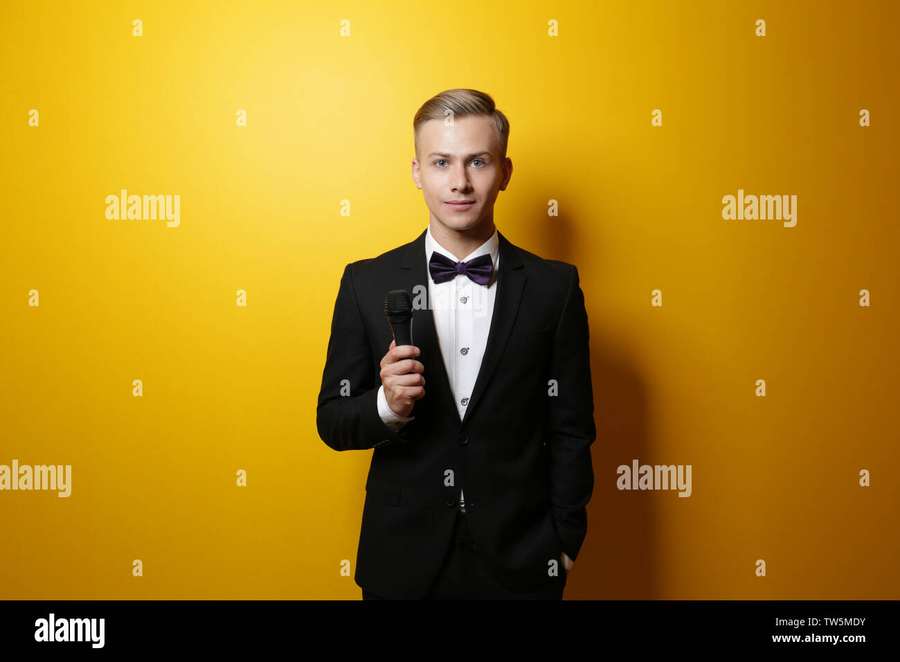 Young presenter with microphone on color background Stock Photo - Alamy