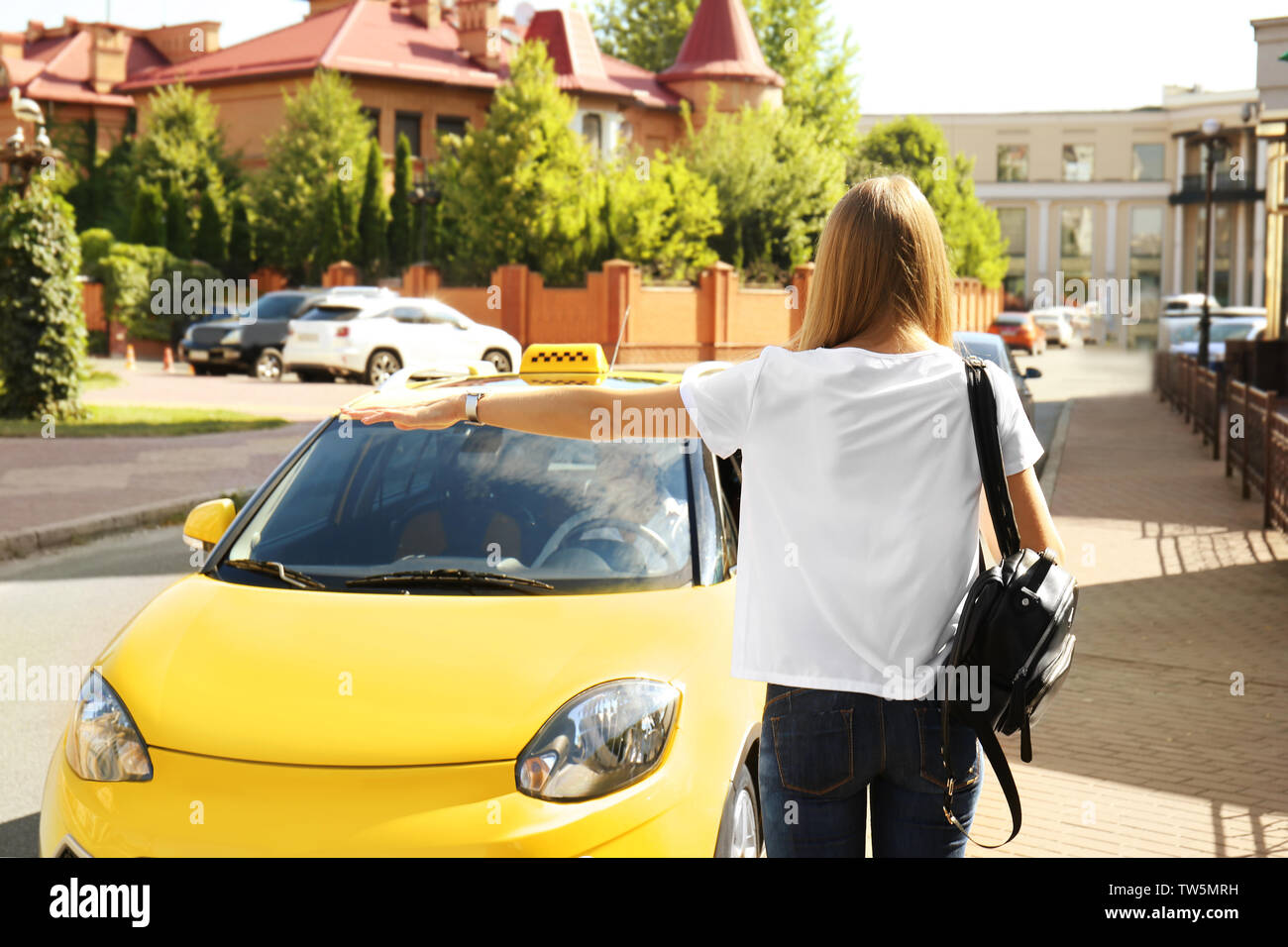 Young woman catching taxi on street Stock Photo - Alamy