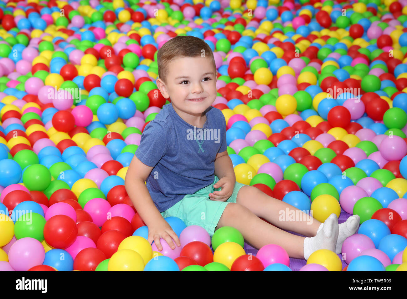 Cute boy playing among plastic balls Stock Photo - Alamy