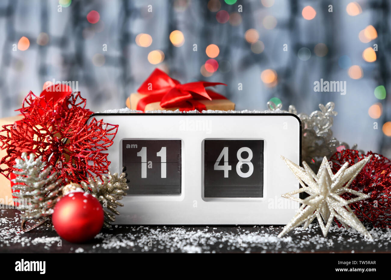 Digital alarm clock and decorations against defocused lights. Christmas ...