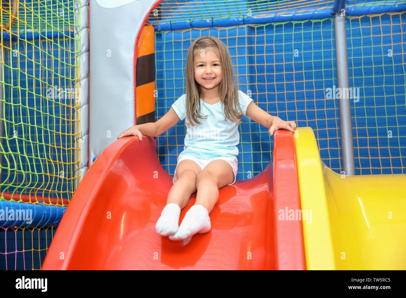 Little girl riding on slide in entertainment center Stock Photo - Alamy