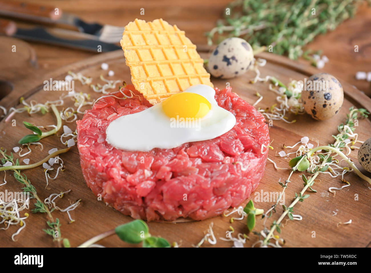 Delicious steak tartare with egg and wafer on wooden board Stock Photo ...