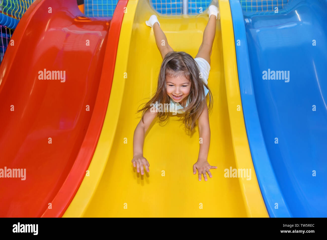 Little girl riding on slide in entertainment center Stock Photo - Alamy