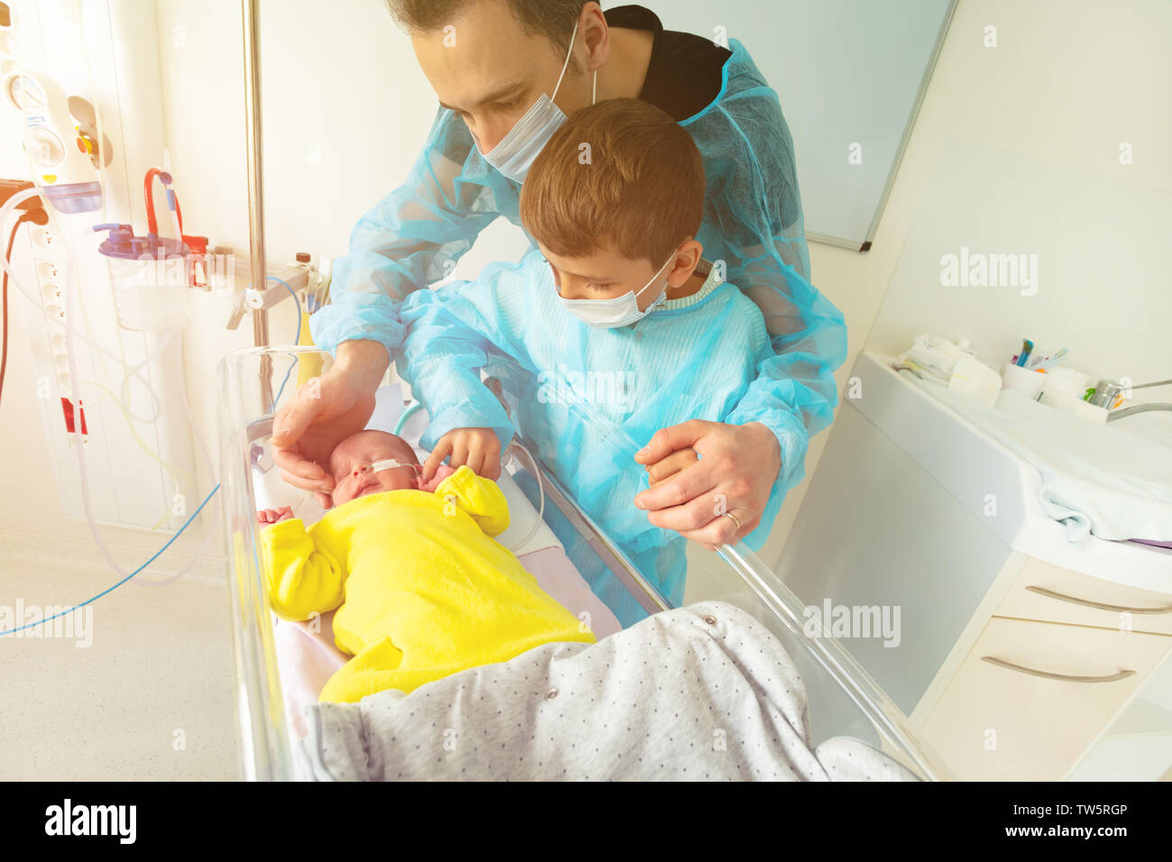 Father and brother with newborn child in hospital Stock Photo - Alamy