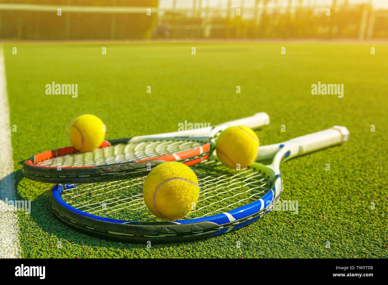 Tennis balls and rackets on court Stock Photo - Alamy