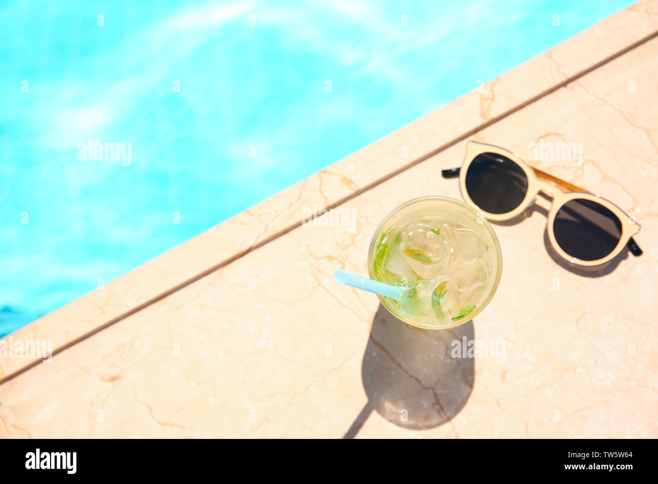 Tasty refreshing cocktail with sunglasses on edge of swimming pool ...